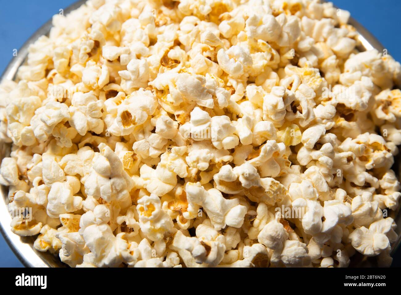 Popcorn in a plate close-up. Blue background Stock Photo - Alamy