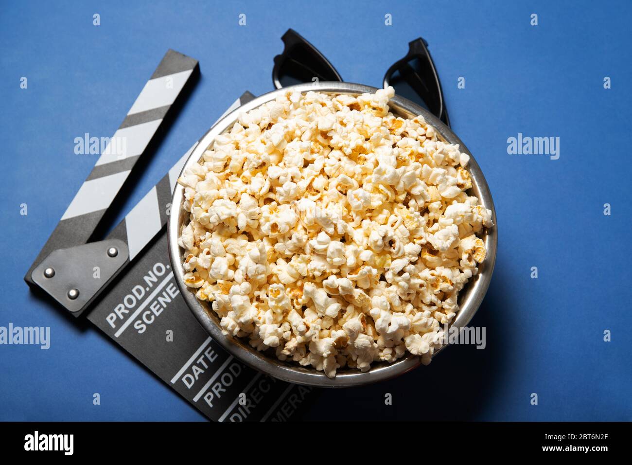 Plate with popcorn and movie clapper board on a blue background Stock ...