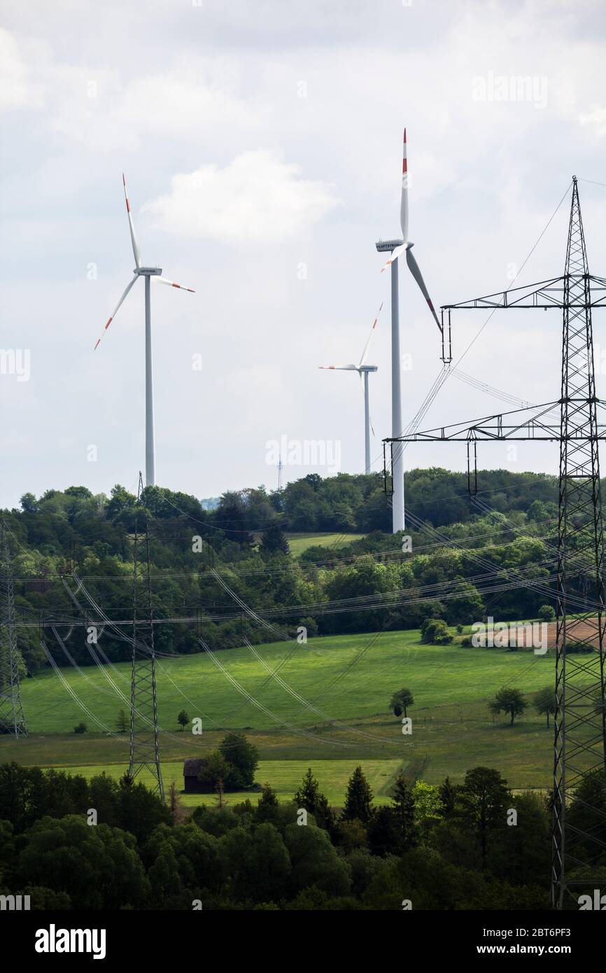 power pylon in the foreground and behind it a wind farm with wind ...