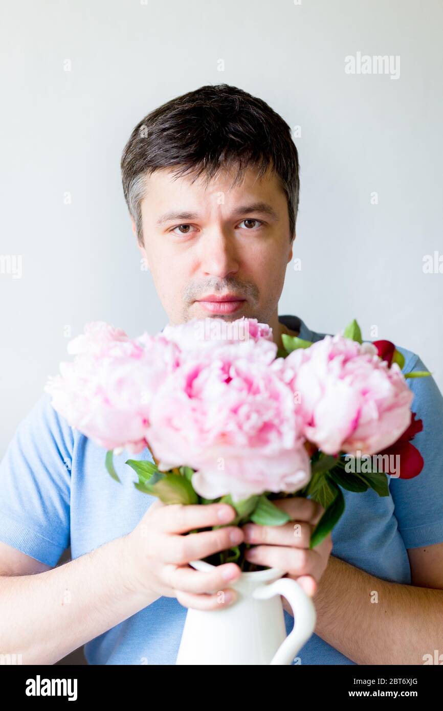 Young Man holding flowers. man in an anti-virus medical mask holds a ...