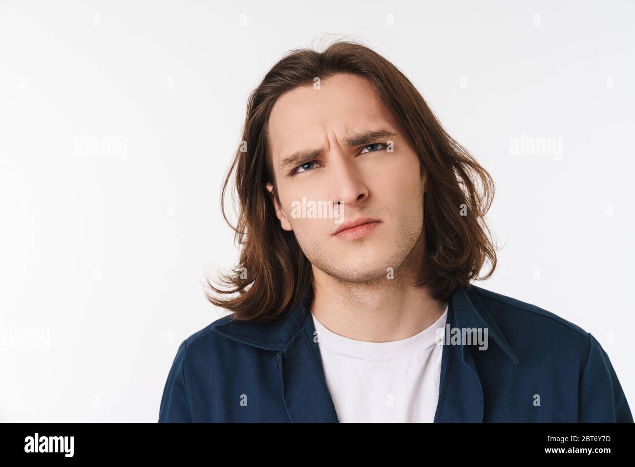 Image of confused handsome man with long hair looking upward and ...