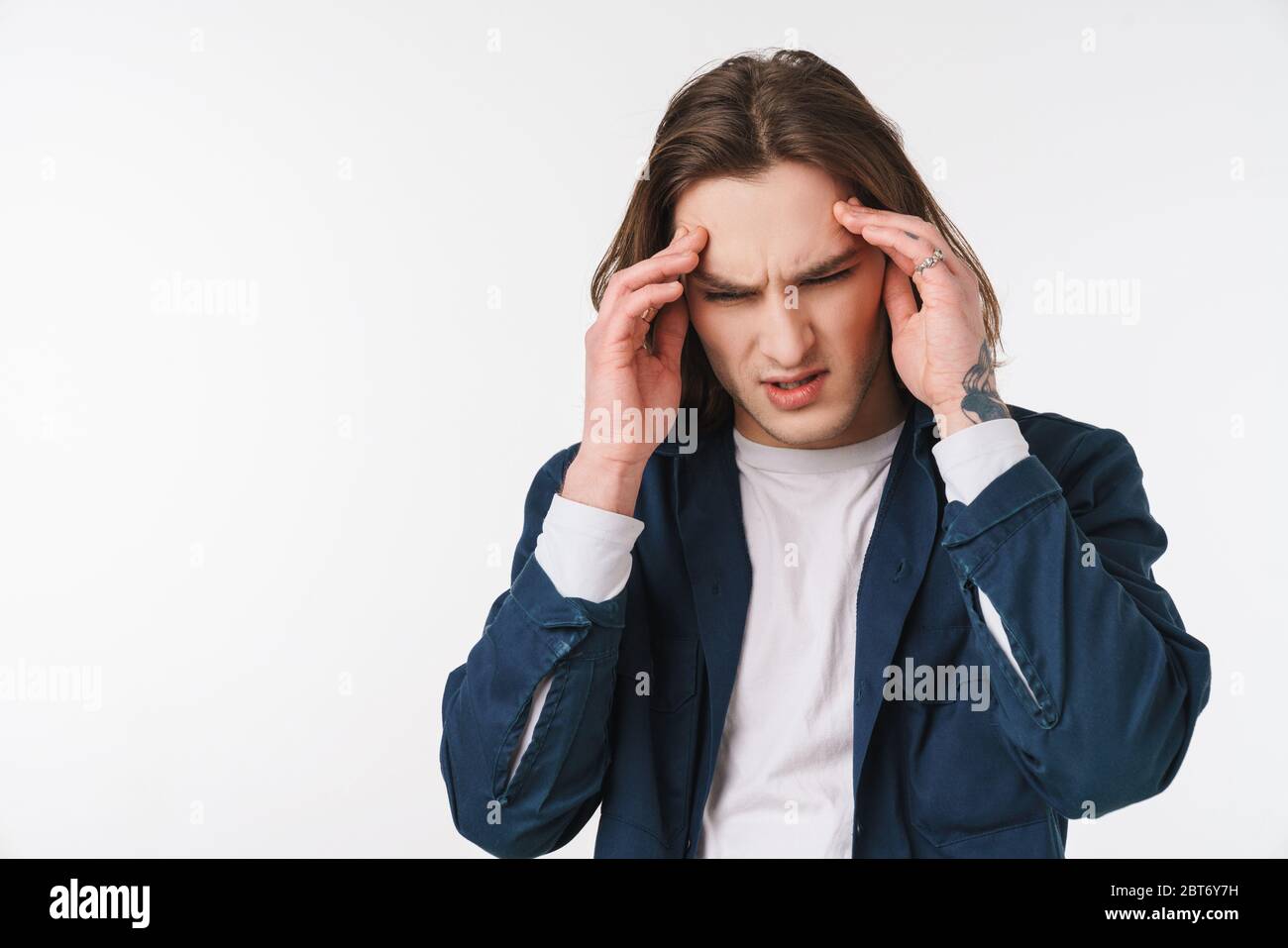 Image of unhappy young man with headache rubbing his forehead isolated ...
