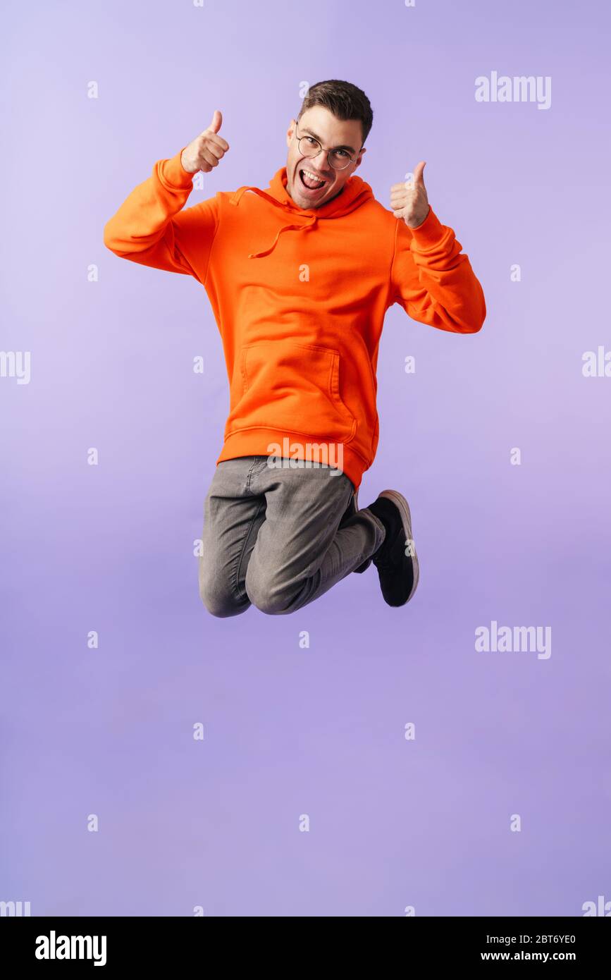 Photo of positive emotional young man jumping isolated over purple ...