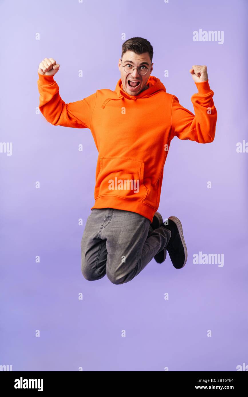 Image of happy emotional young man jumping isolated over purple ...