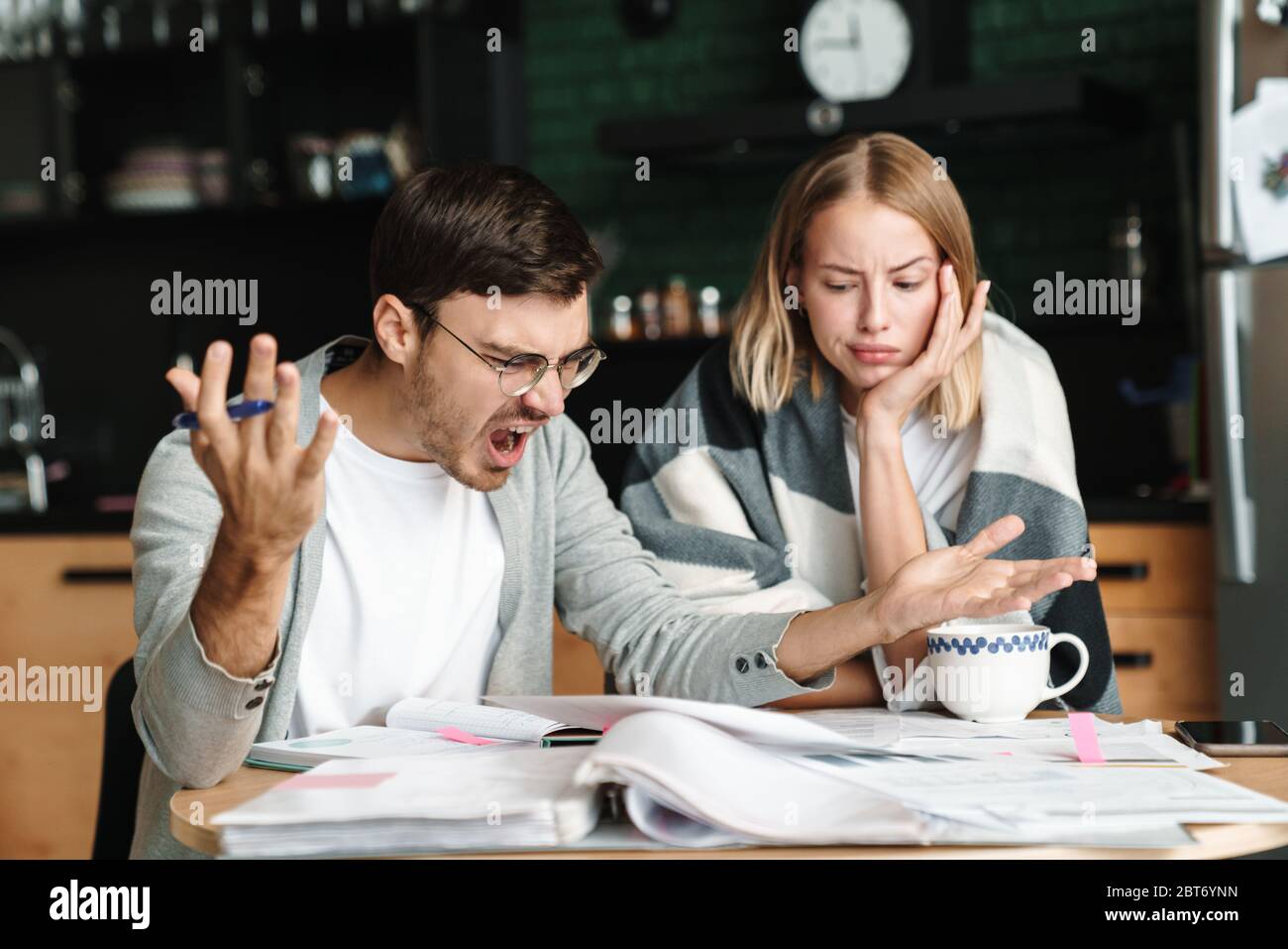 Image of confused young businesslike man and woman doing calculations ...