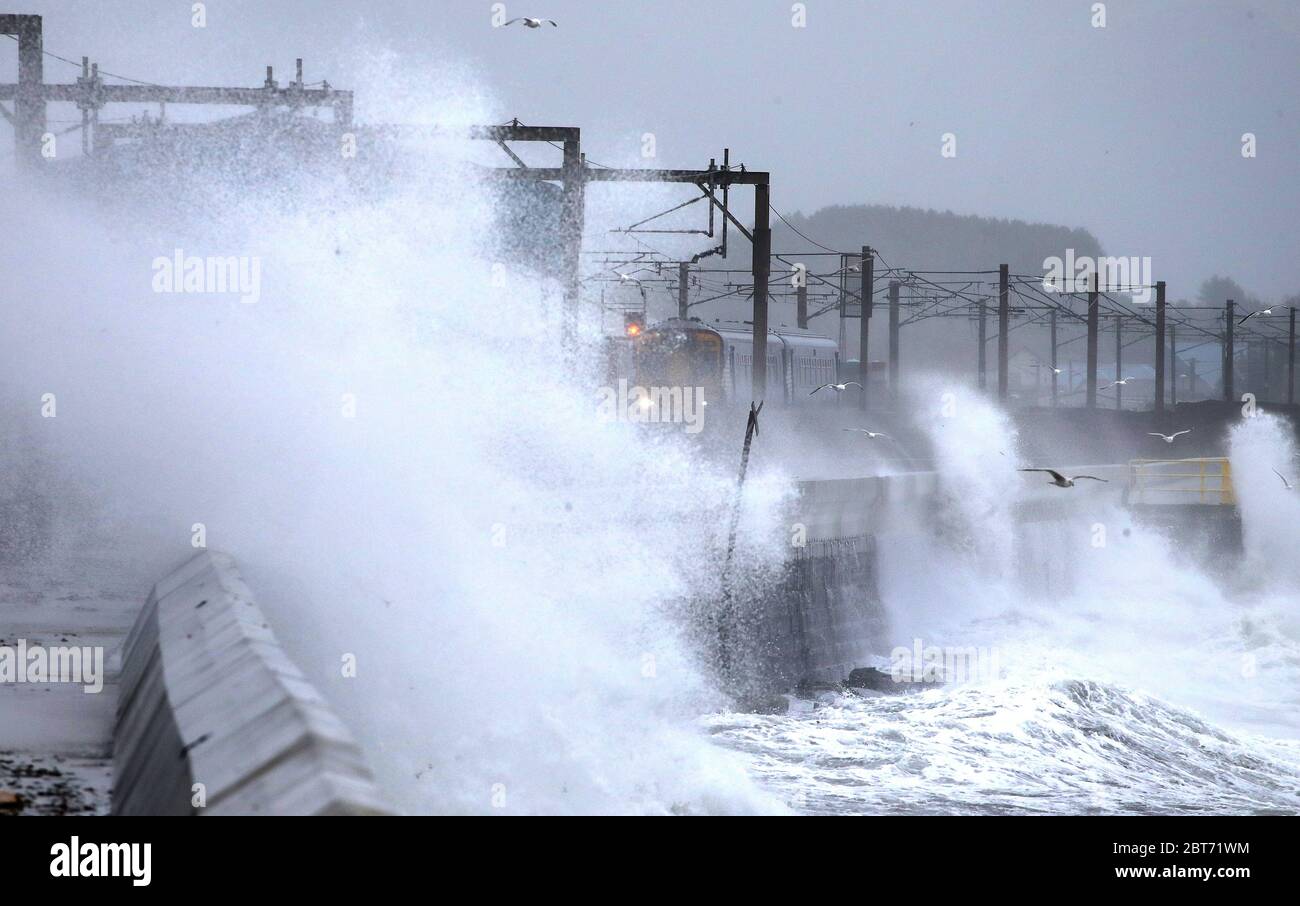 A train passes as waves crash at the seafront at Saltcoats, as the hot ...