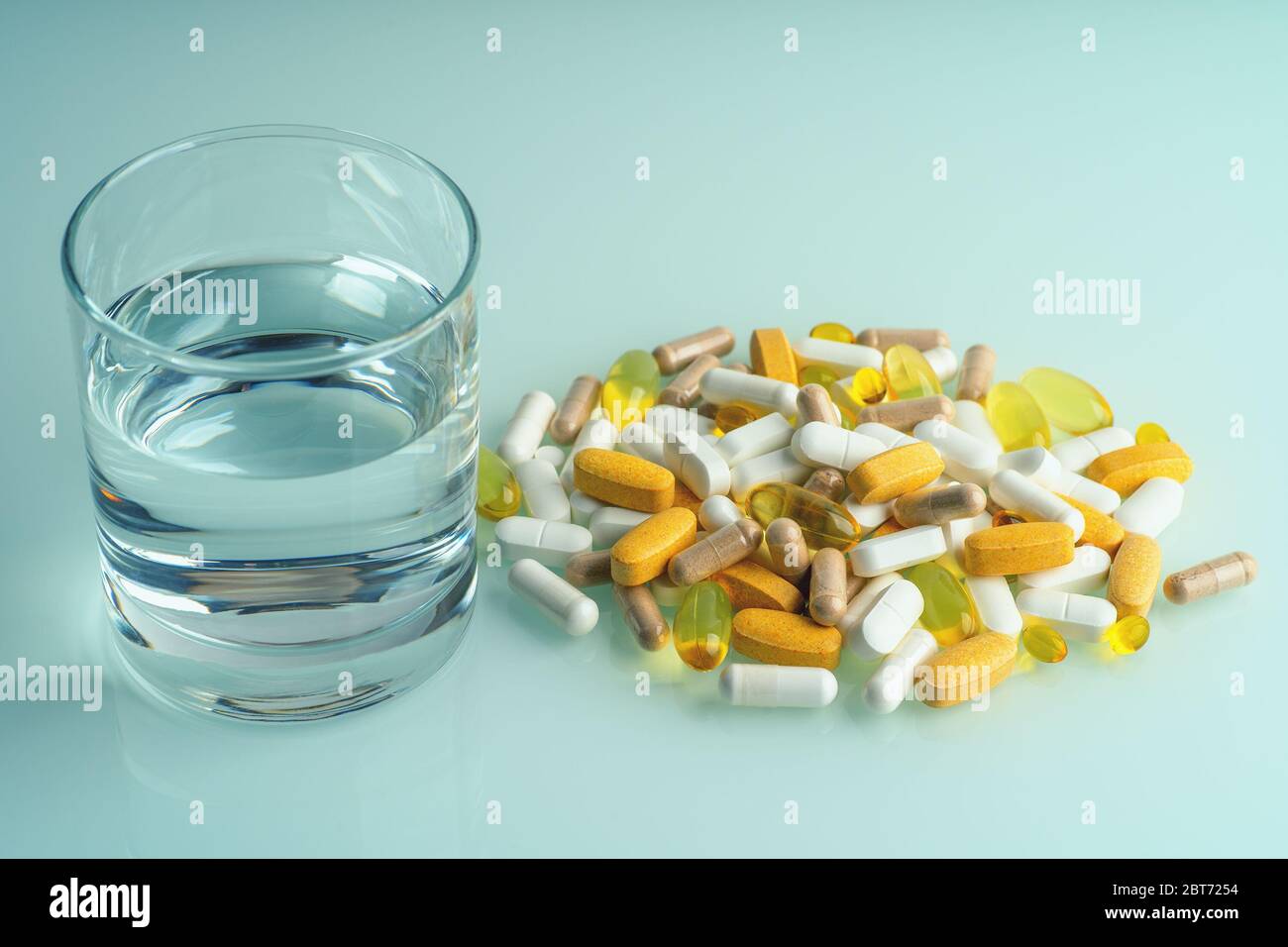 Medicaments, pill capsules, drugs and dietary supplements with water glass close up. Medication ...