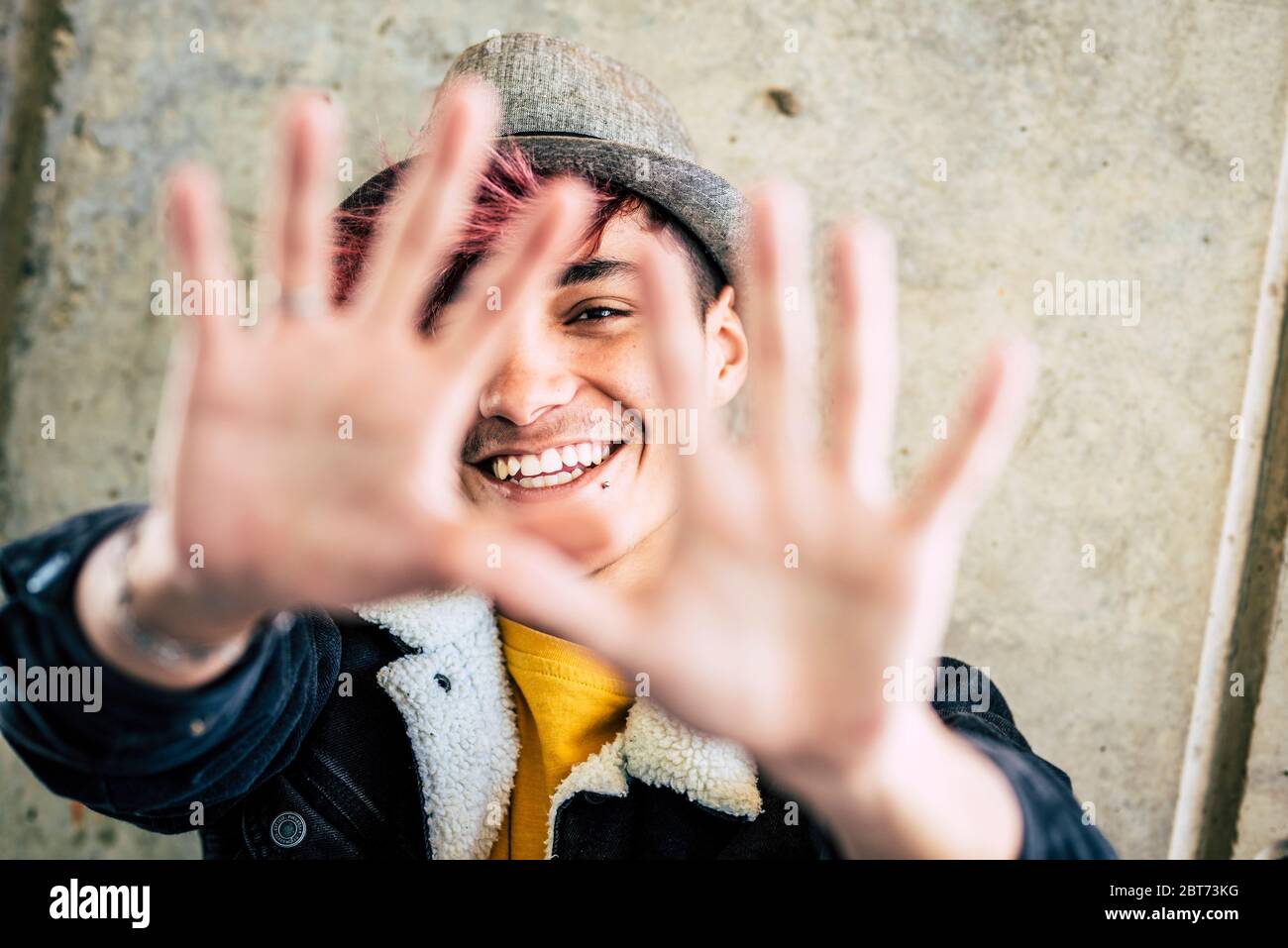 Alternative happy and cheerful diverse teenager hide his face and smile ...