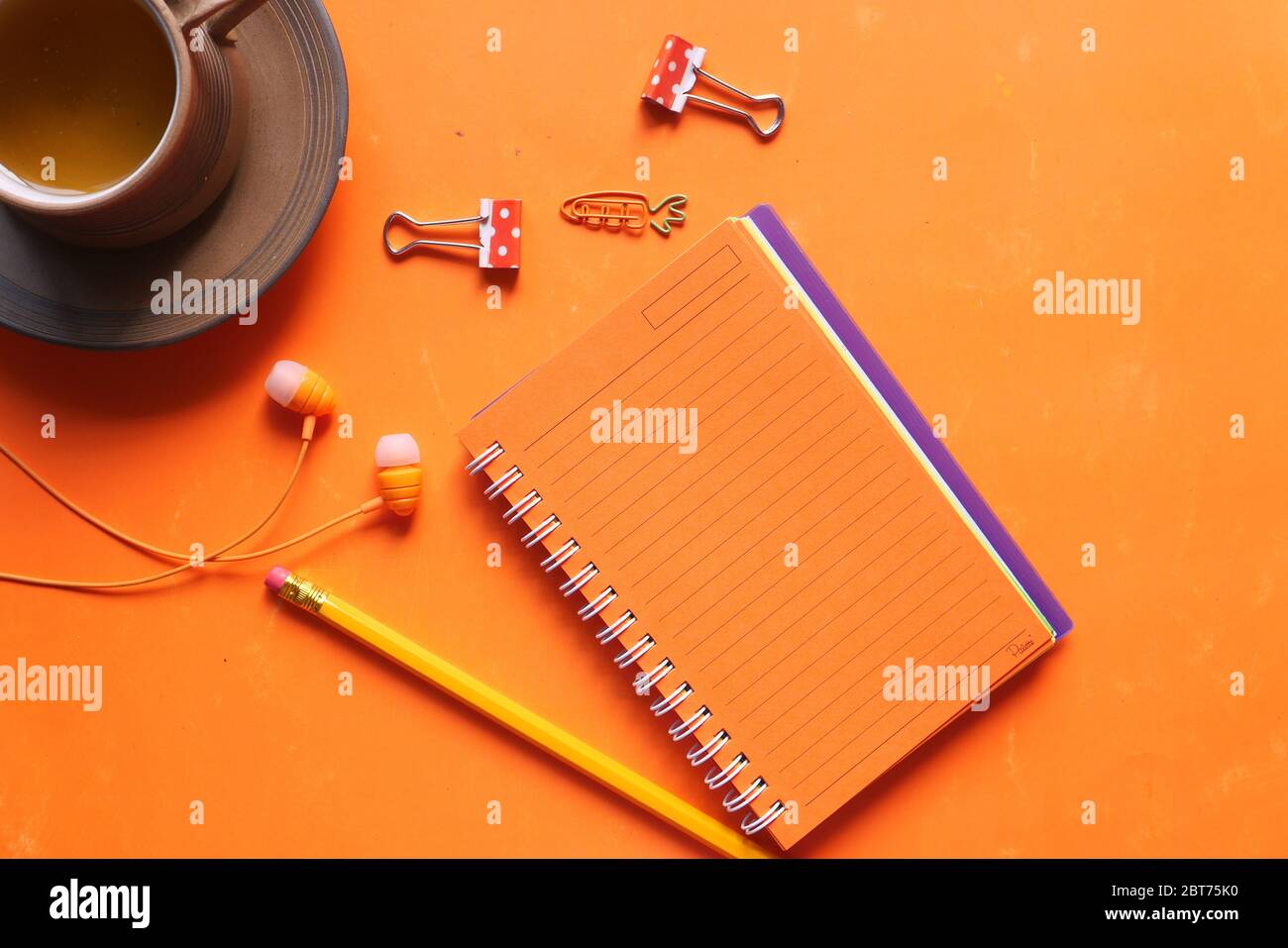 open colorful notepad and pens on orange background Stock Photo - Alamy