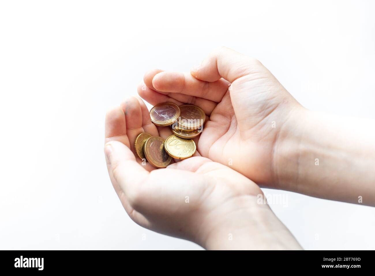 Closeup child's hands holding Euro coins isolated on white background ...