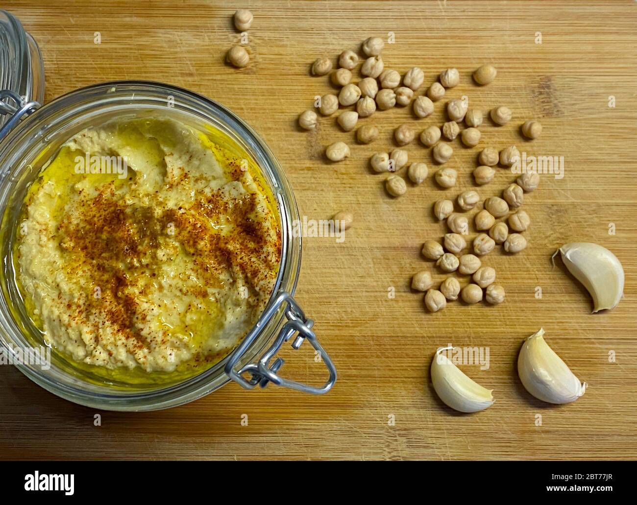 Homemade hummus in glass jar with chickpea beans and garlic cloves on ...