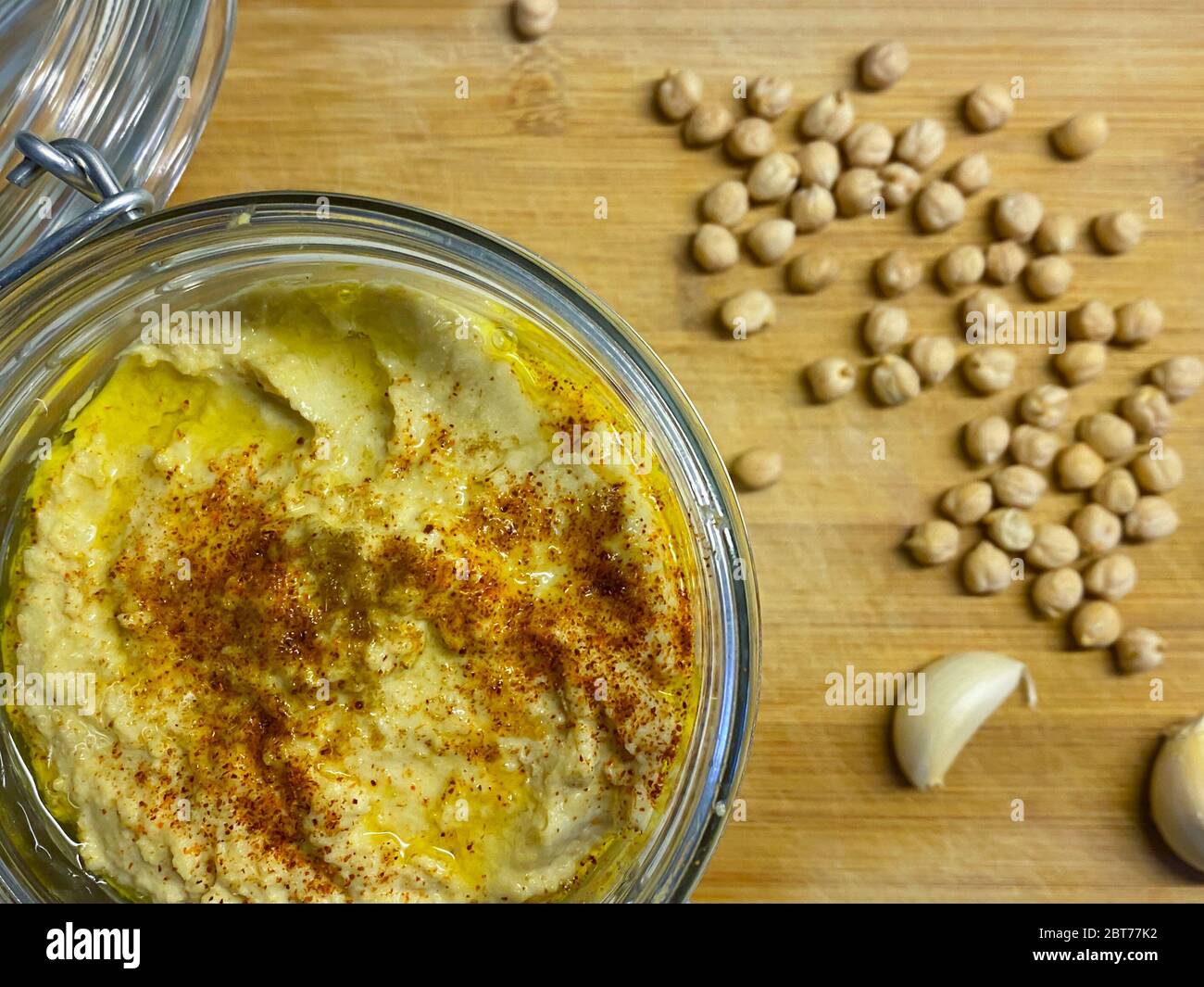 Homemade hummus in glass jar with chickpea beans and garlic cloves on ...