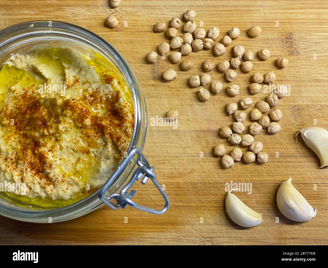 Homemade hummus in glass jar with chickpea beans and garlic cloves on ...