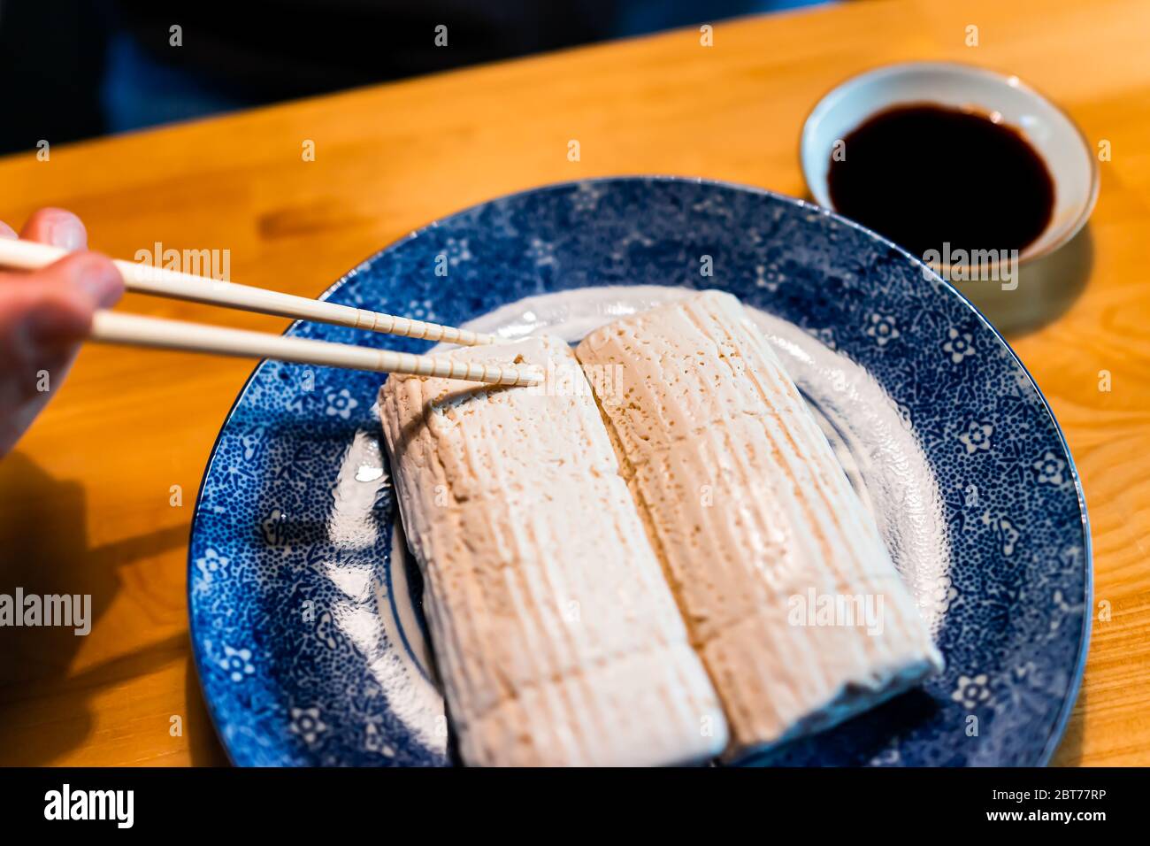Closeup of hand holding chopsticks cutting Japanese traditional komo ...