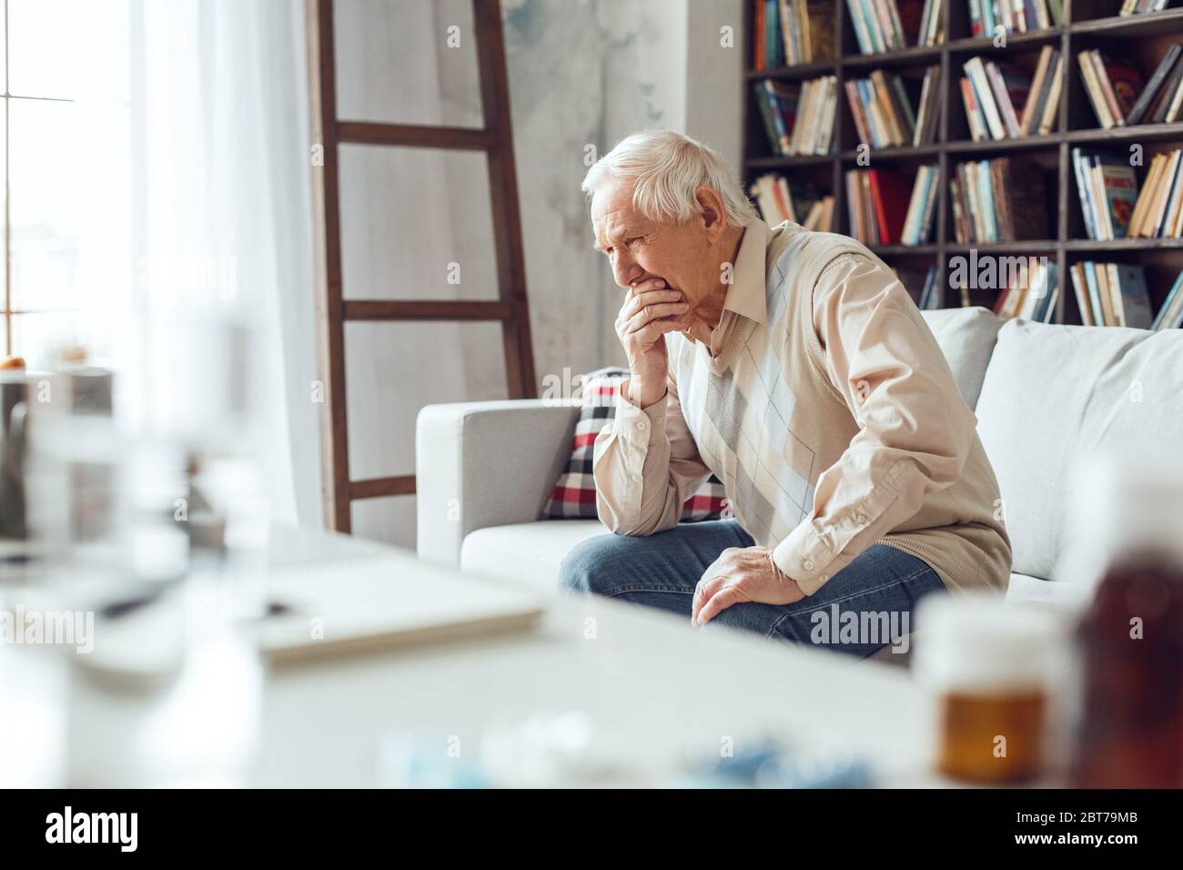 Senior man alone sitting at library table close-up crying emotional ...