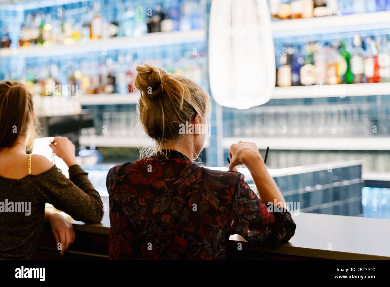 Blonde woman on her back sitting at a bar decorated with blue tiles and ...