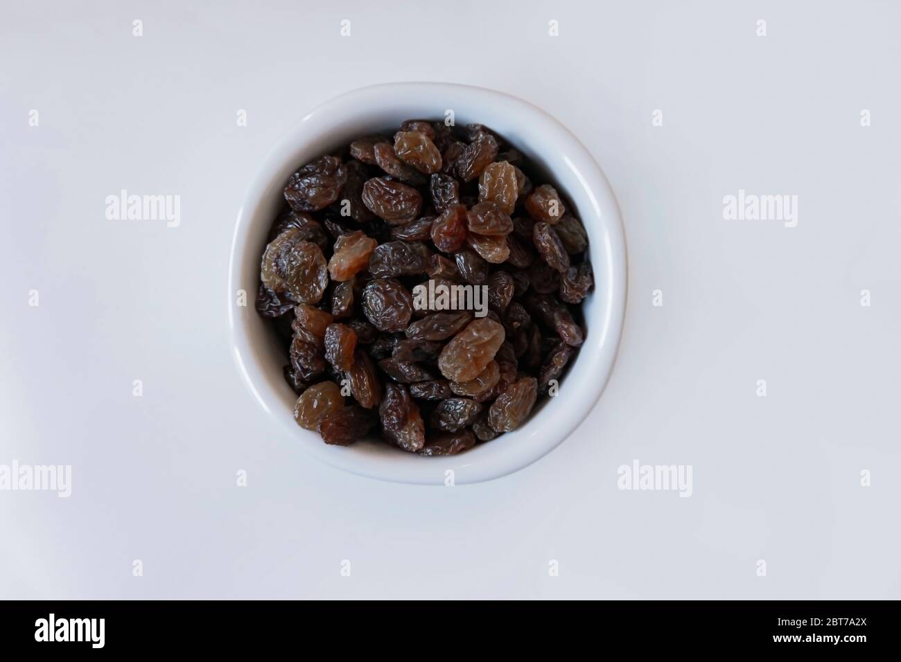 dry raisins isolated in white pot Stock Photo - Alamy