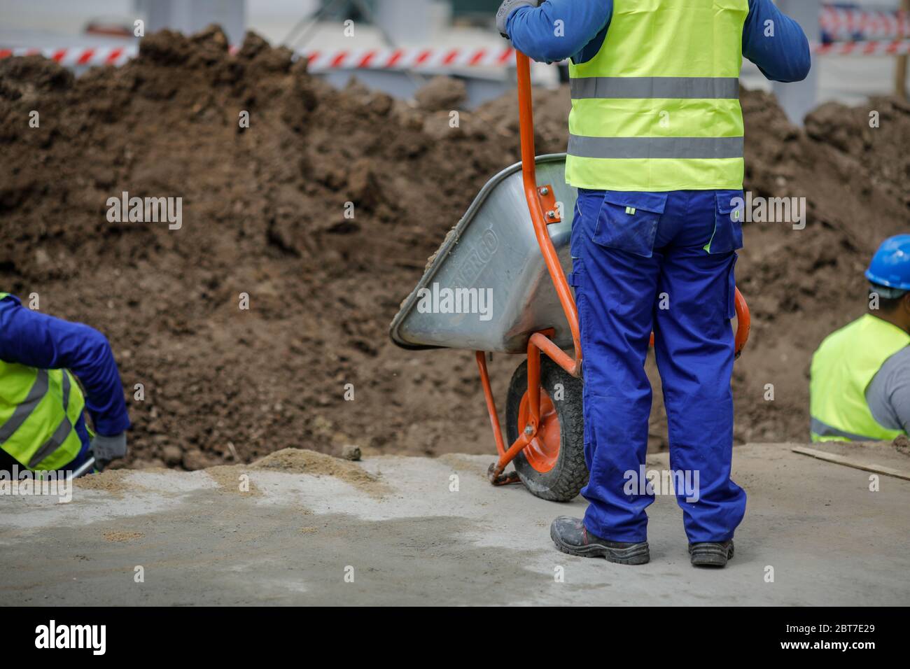 Details with a construction worker pushing a wheelbarrow on a ...