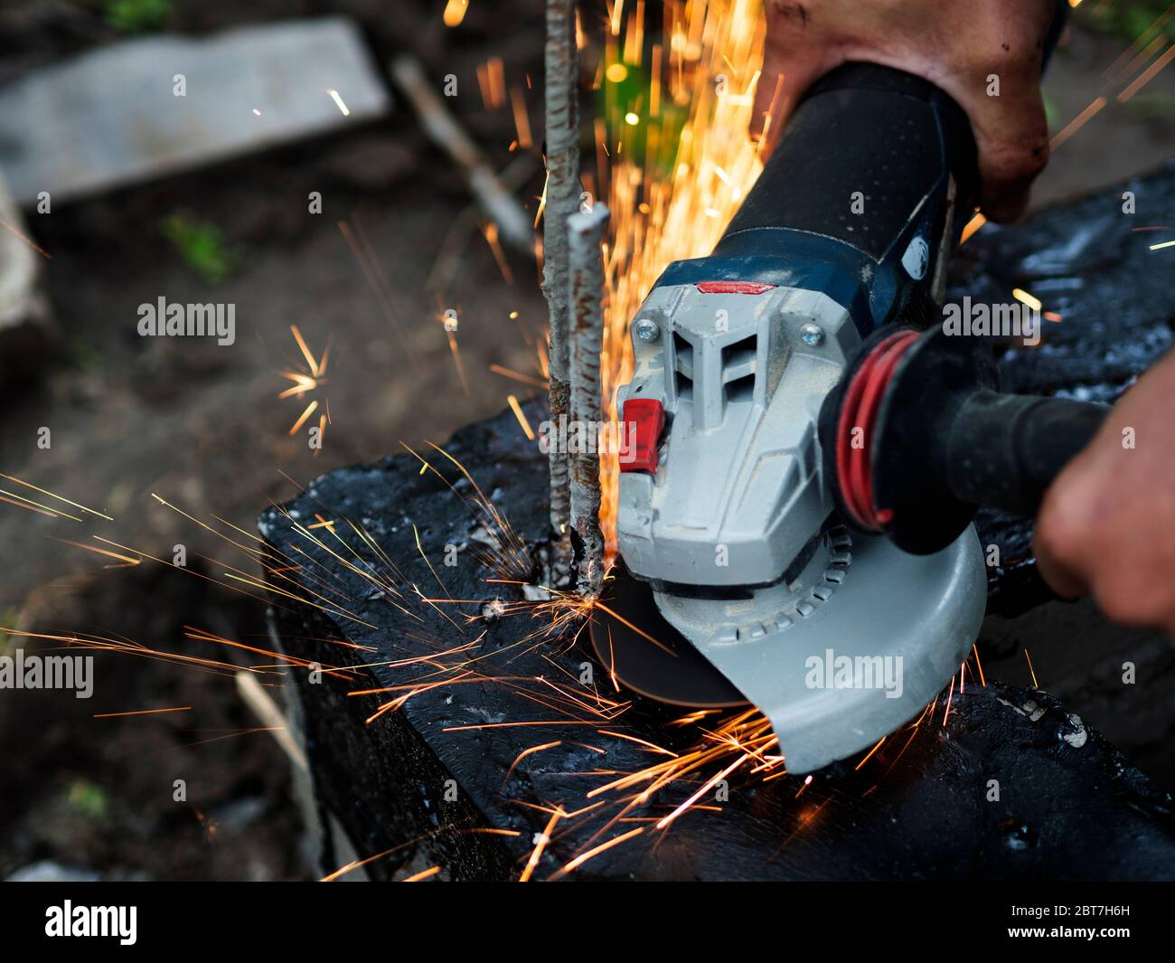 Worker cuts off excess reinforcement in the foundation using an angle ...