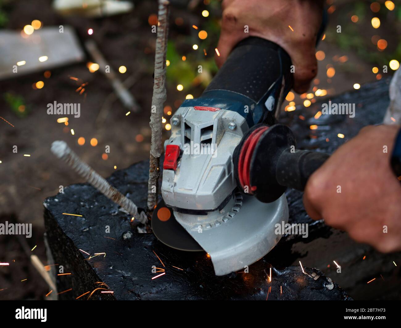Worker cuts off excess reinforcement in the foundation using an angle ...