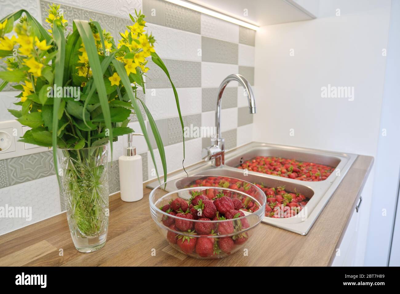 Strawberry season, washing berries in water in wash basin at home ...