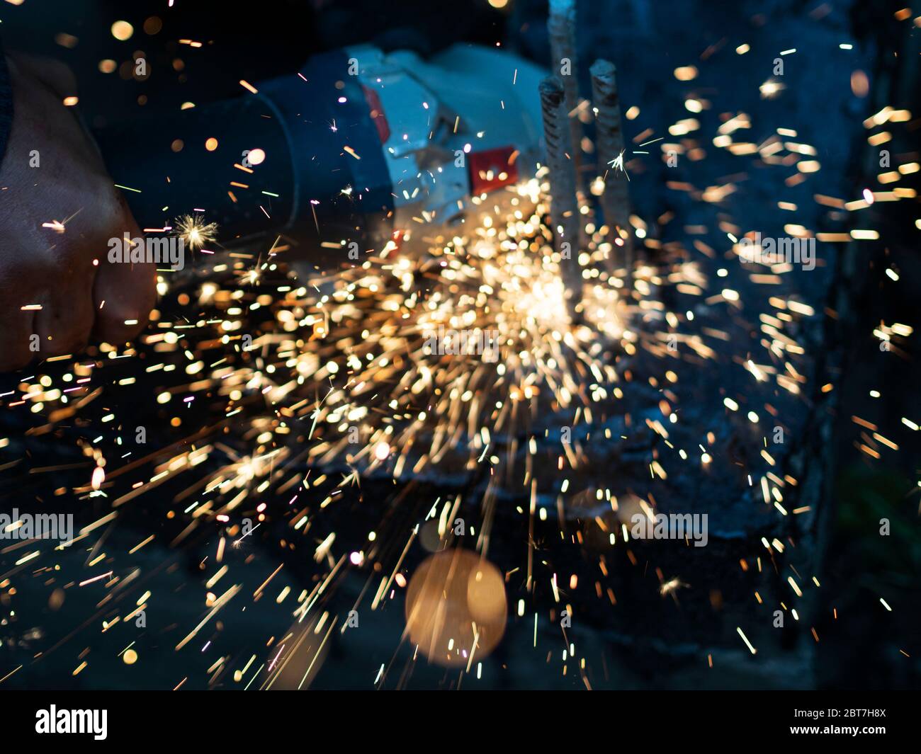 Worker cuts off excess reinforcement in the foundation using an angle ...