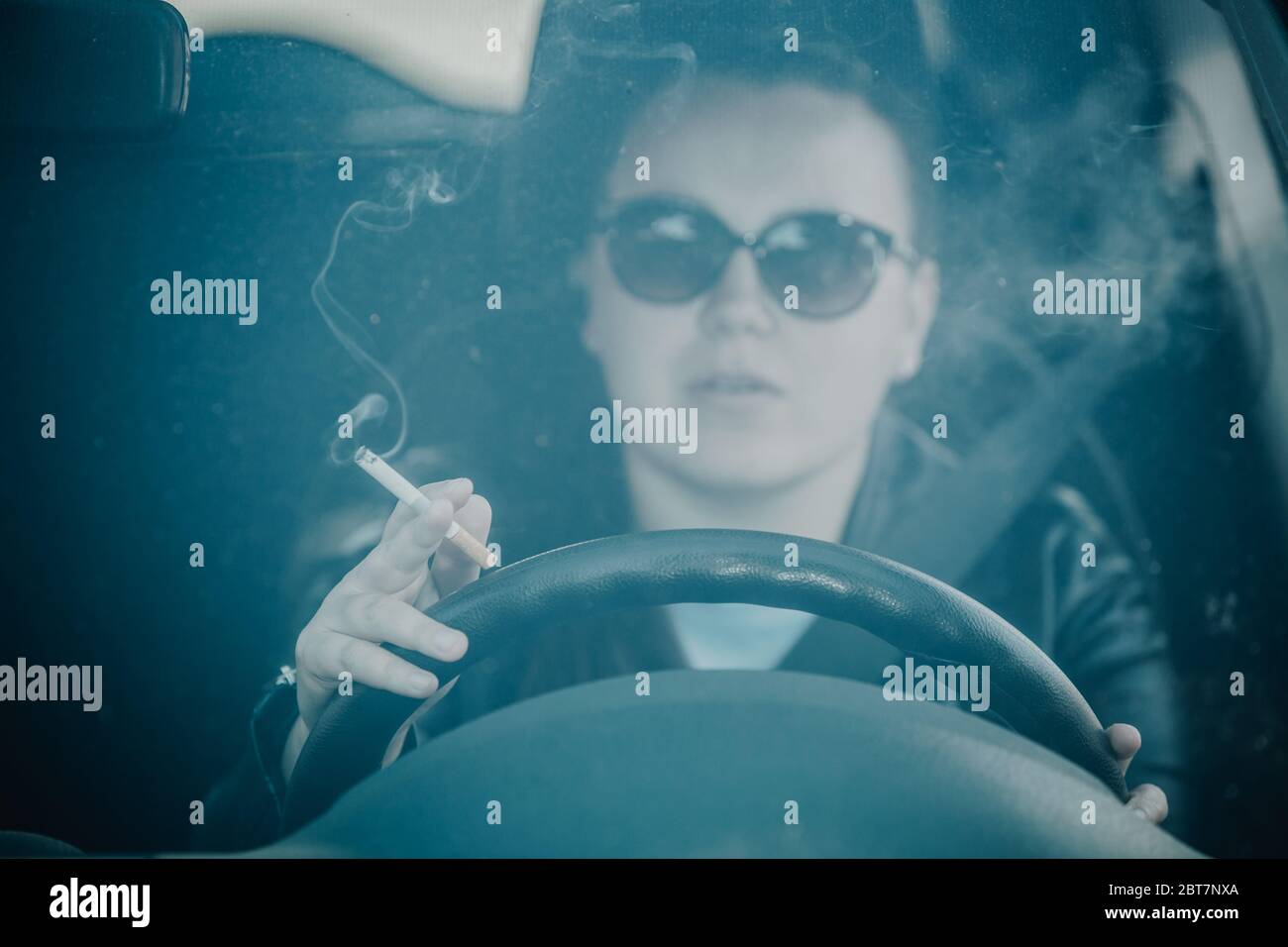 Close up of woman hand smoking cigarette inside the car while driving a ...
