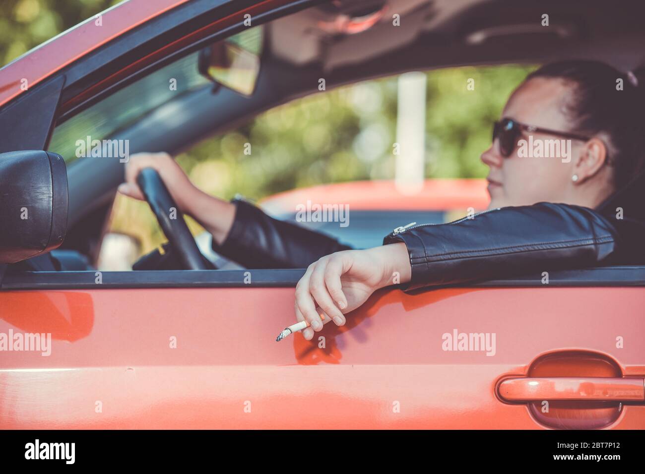 Close up of woman hand smoking cigarette inside the car while driving a ...