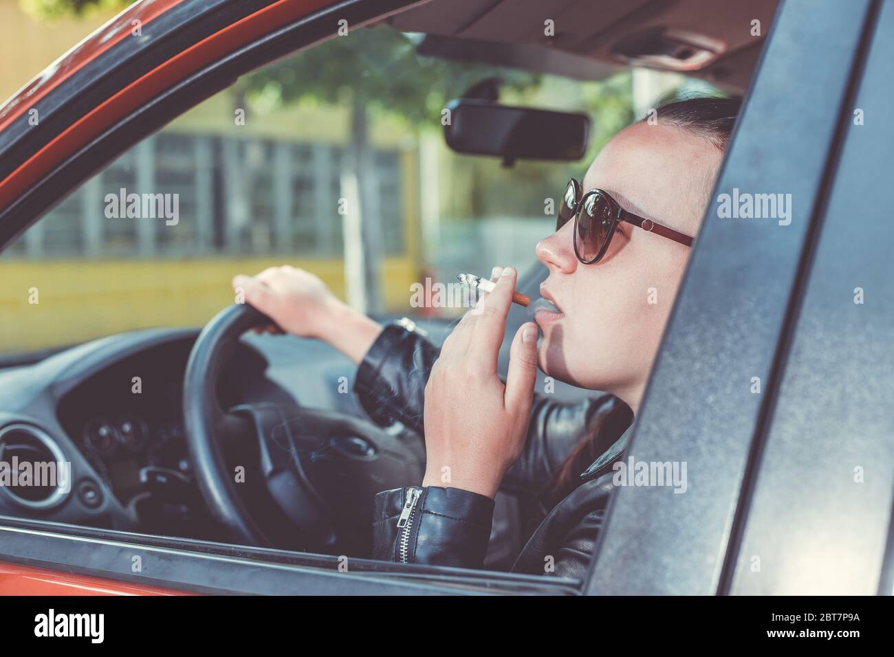 Close up of woman hand smoking cigarette inside the car while driving a ...