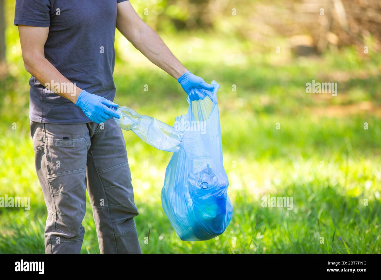 Plastic planet, man picking up plastic bottle, garbage collecting in a ...