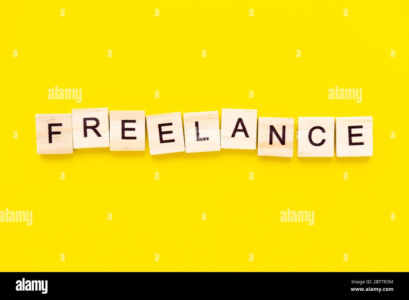 word freelance. Wooden blocks with lettering on top of yellow ...