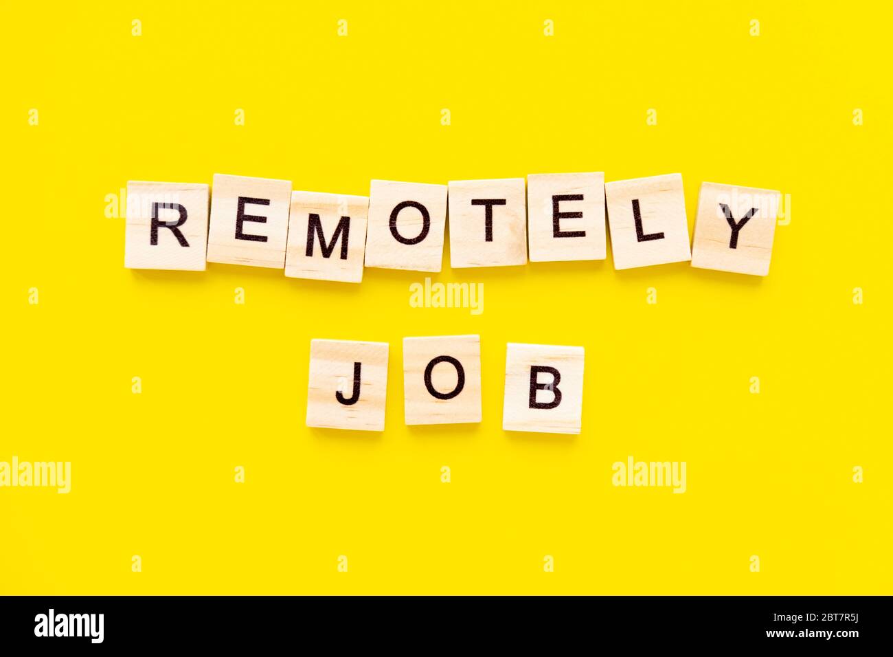 words remotely job. Wooden blocks with lettering on top of yellow ...