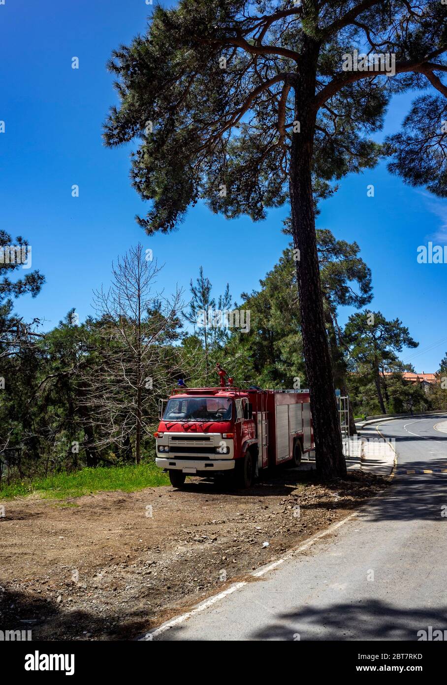 Red fire truck on a forest mountain road in the hot summer in the ...