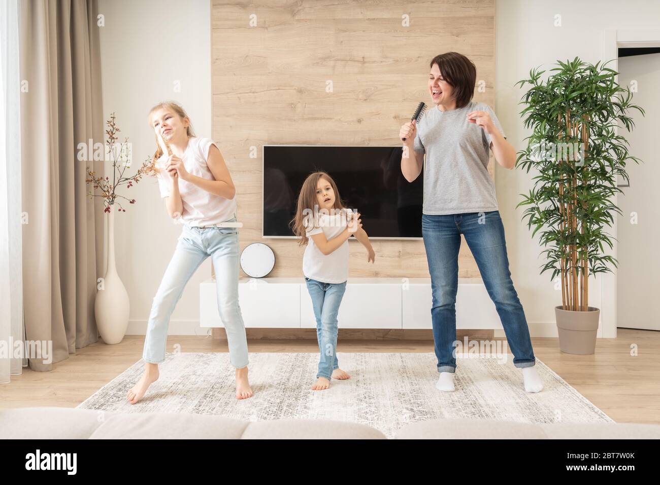 Happy mother and two daughters having fun singing karaoke song in ...