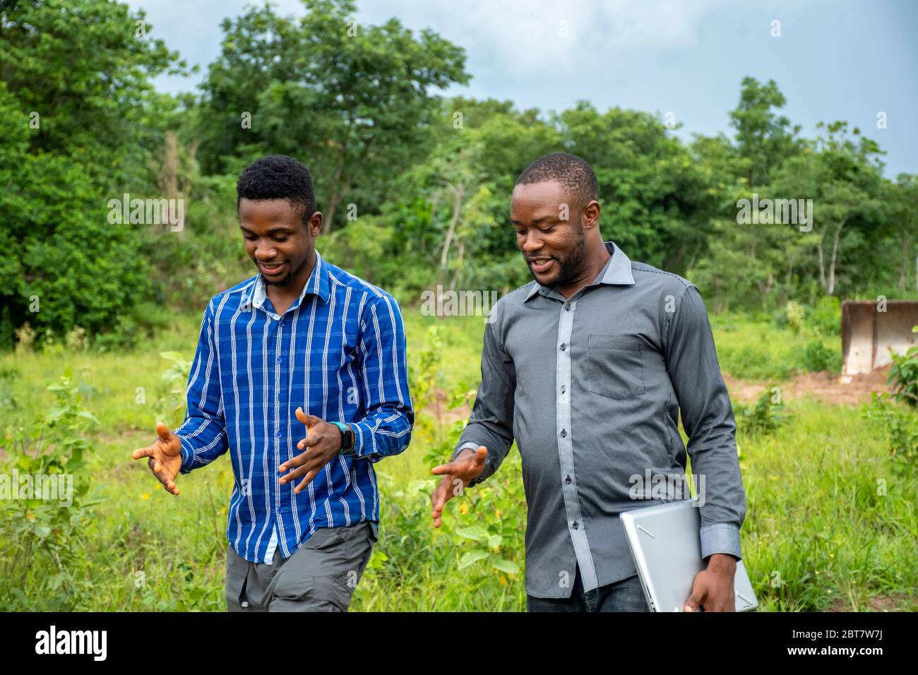 two young african business men, discussing while walking on a plot of ...