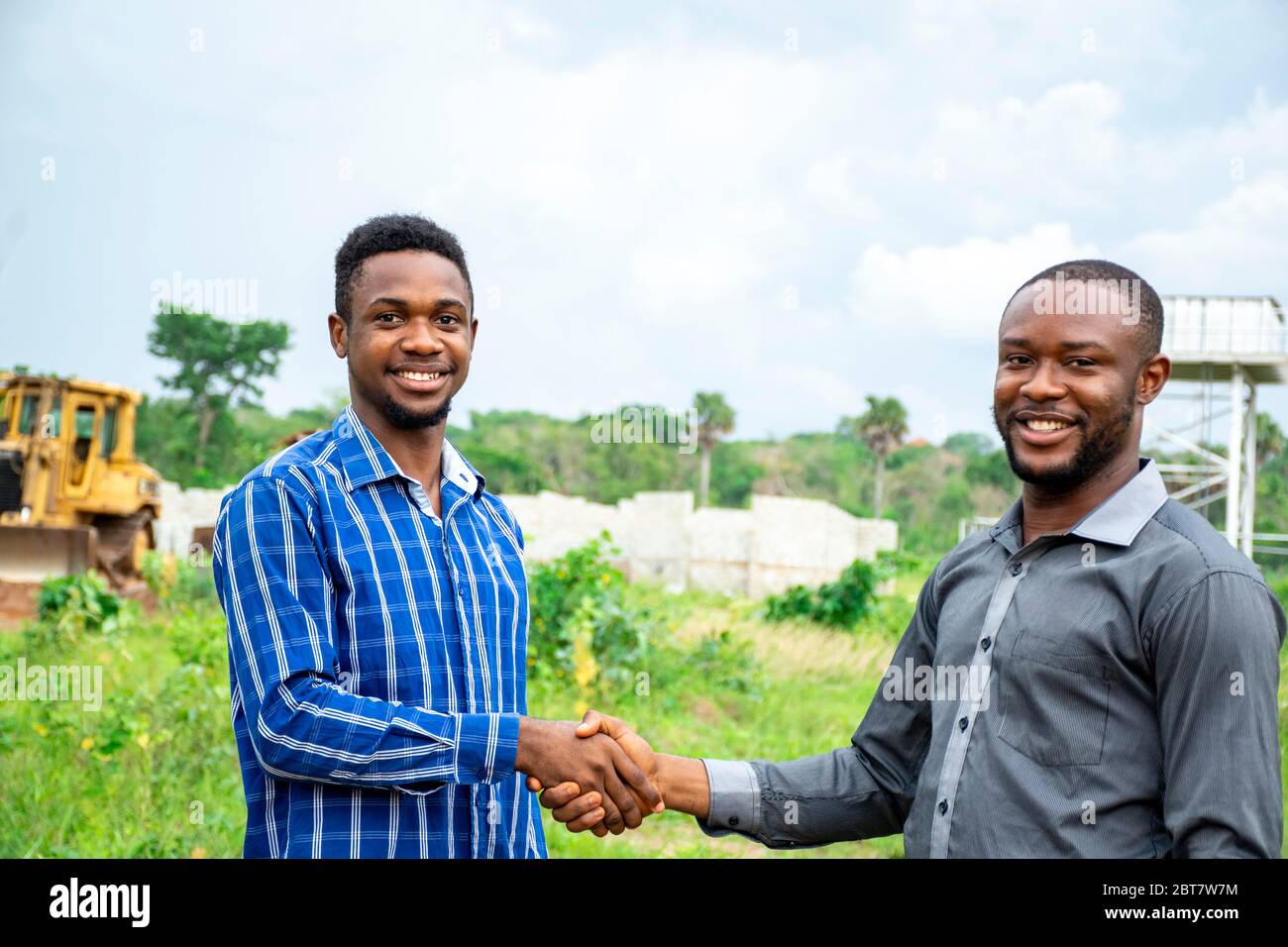 two african business men shake hands, smiling as they are satisfied ...