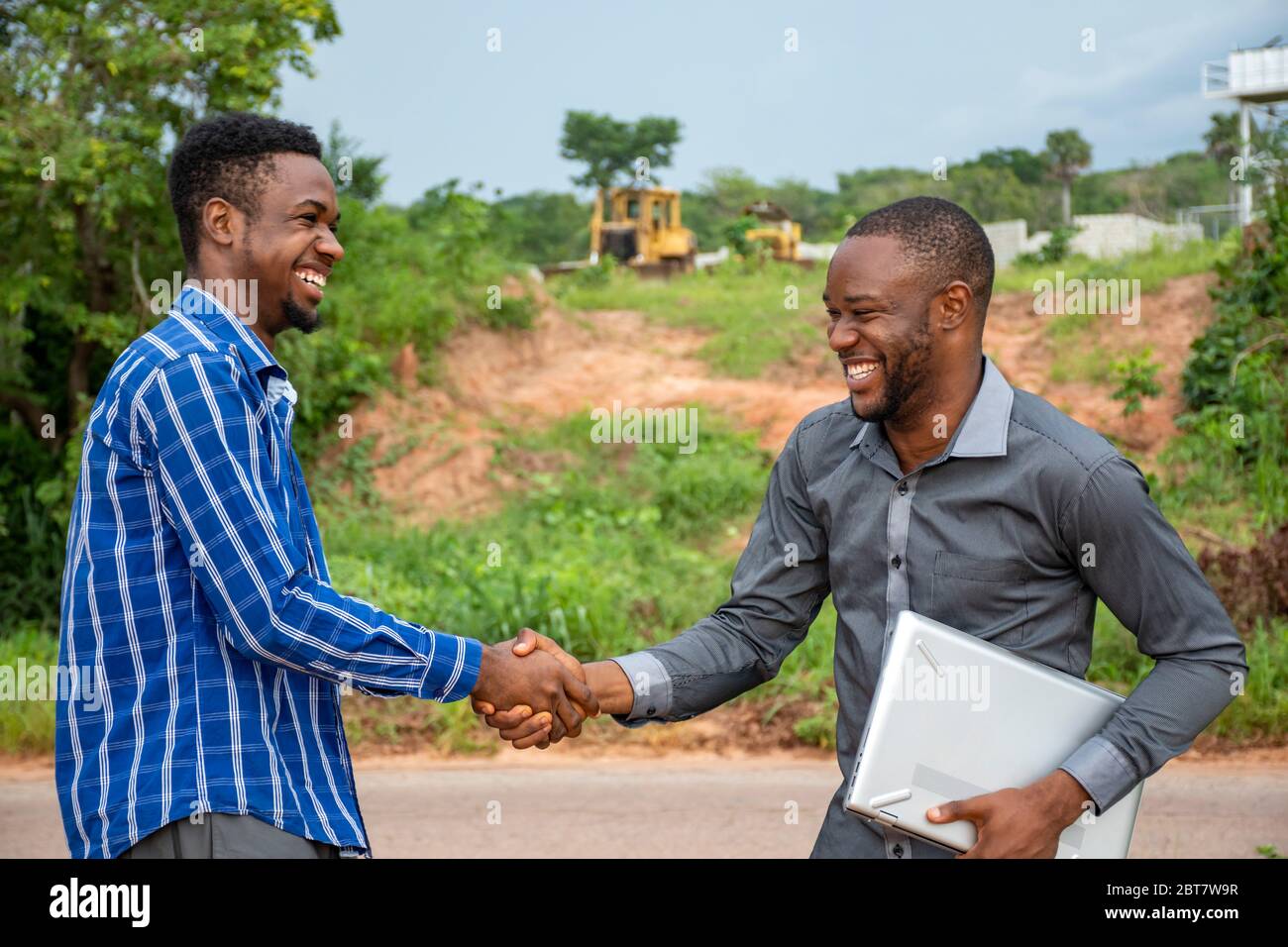 two young african modern farmers shake hands, satisfied with a deal ...