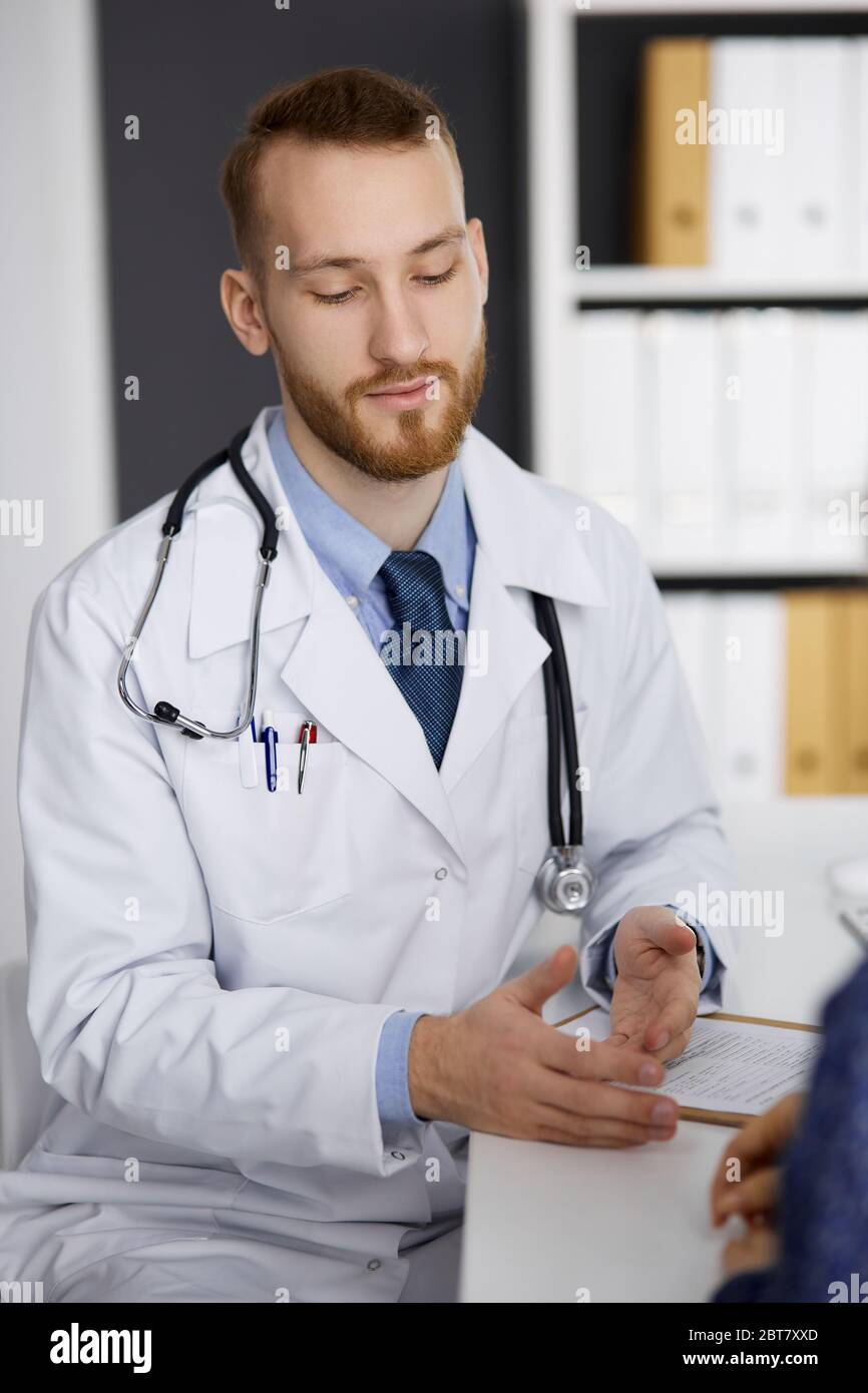 Friendly red-bearded doctor and patient woman discussing current health ...