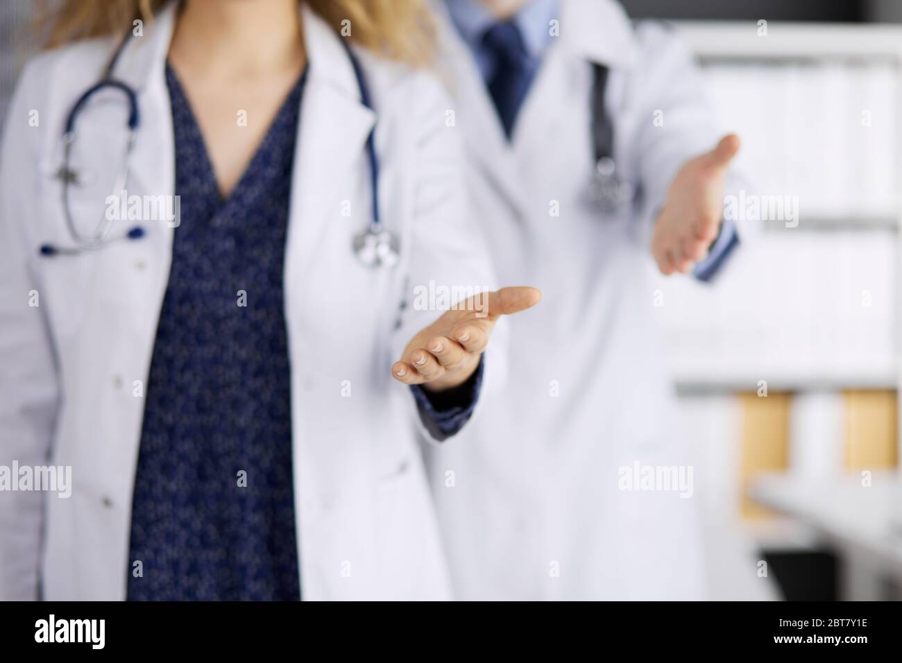 Two doctors standing and offering helping hand for shaking hand or ...