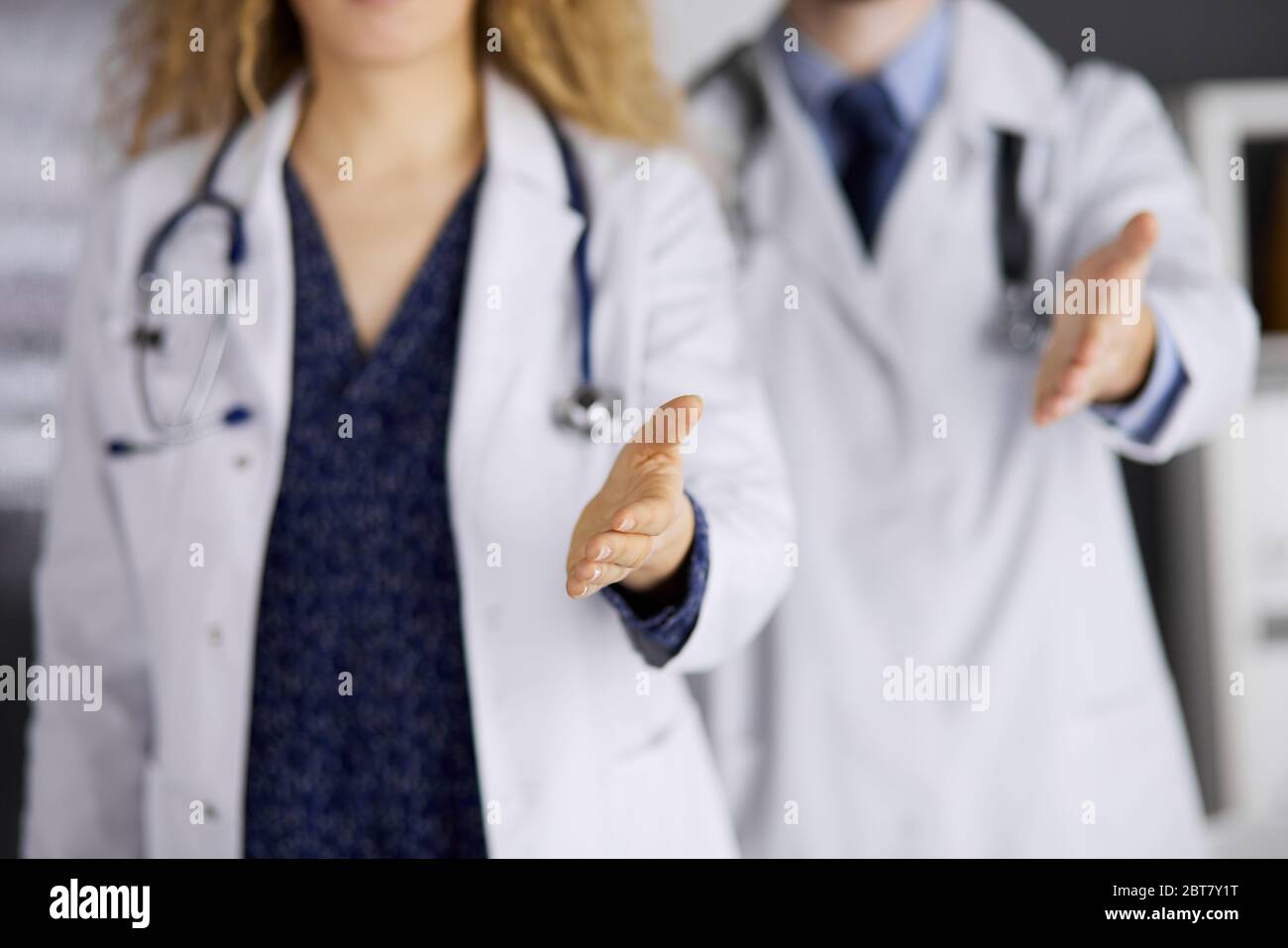 Two doctors standing and offering helping hand for shaking hand or ...