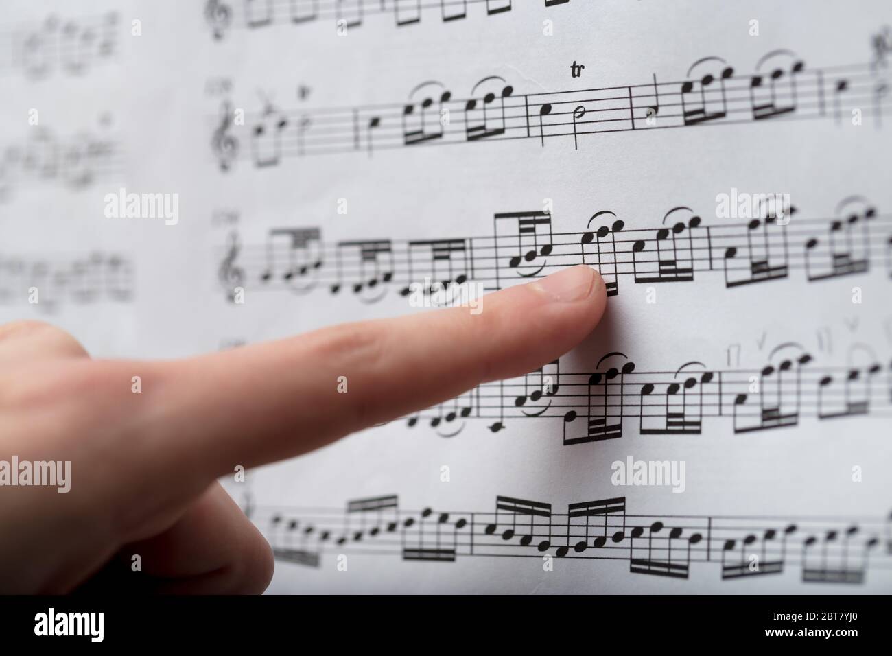 Female finger following the notes on a classical music score in a close ...