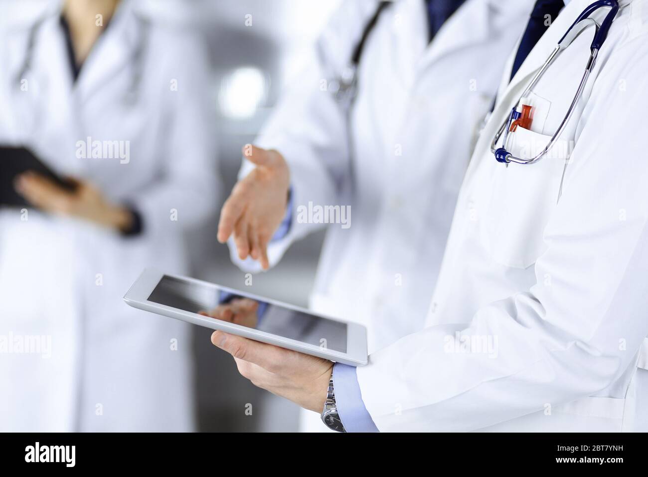 Group of unknown doctors use a computer tablet to check up some medical ...