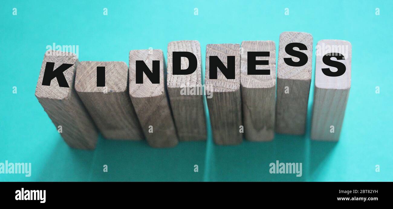 KINDNESS word made with wooden building blocks on neon aquamarine ...