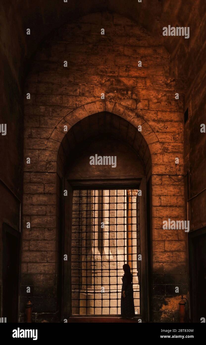 The worshiper. A girl standing in front of an ancient Large window. The ...