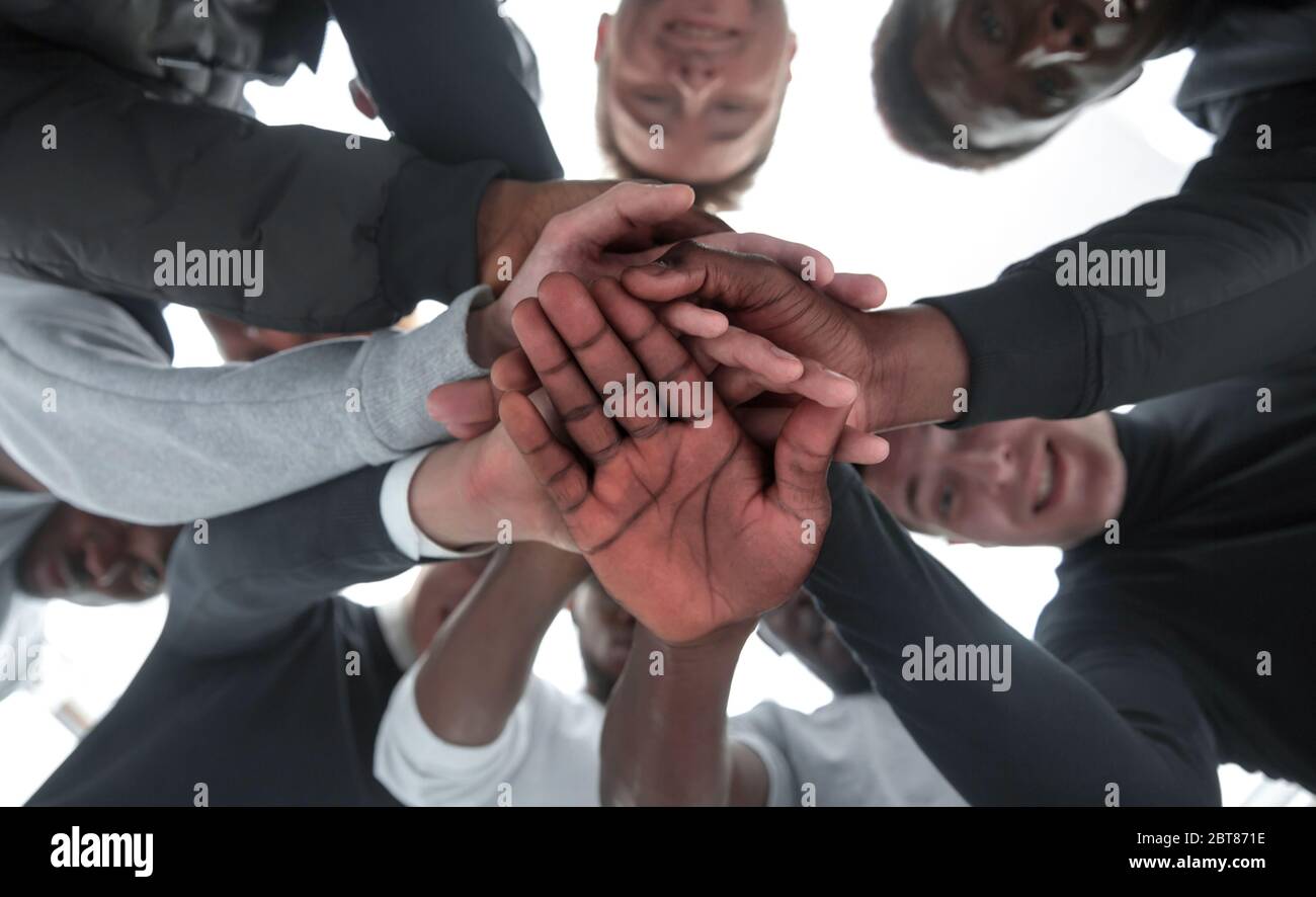 bottom view. a group of diverse young people joining their hands ...
