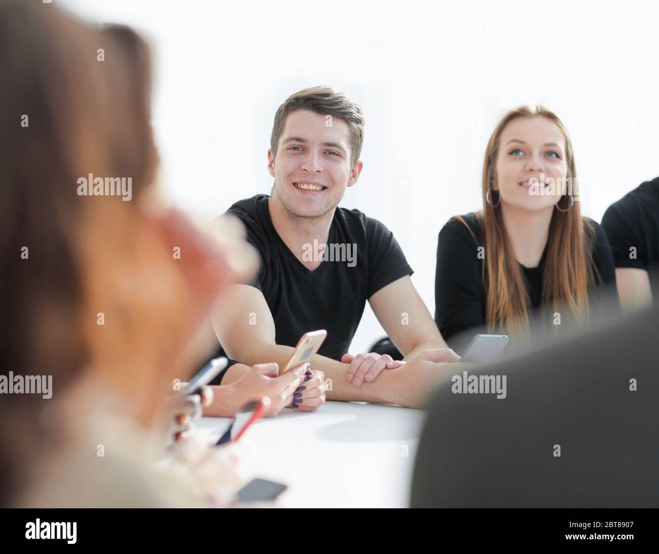 group of young people sitting at a round table Stock Photo - Alamy