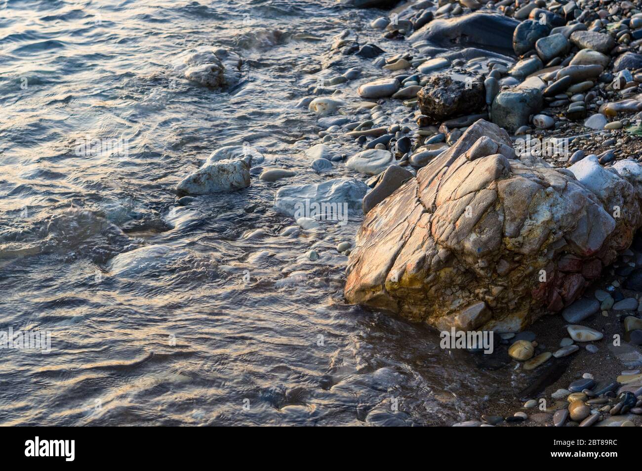 pebble stones on the sea beach, the rolling waves of the sea with foam ...