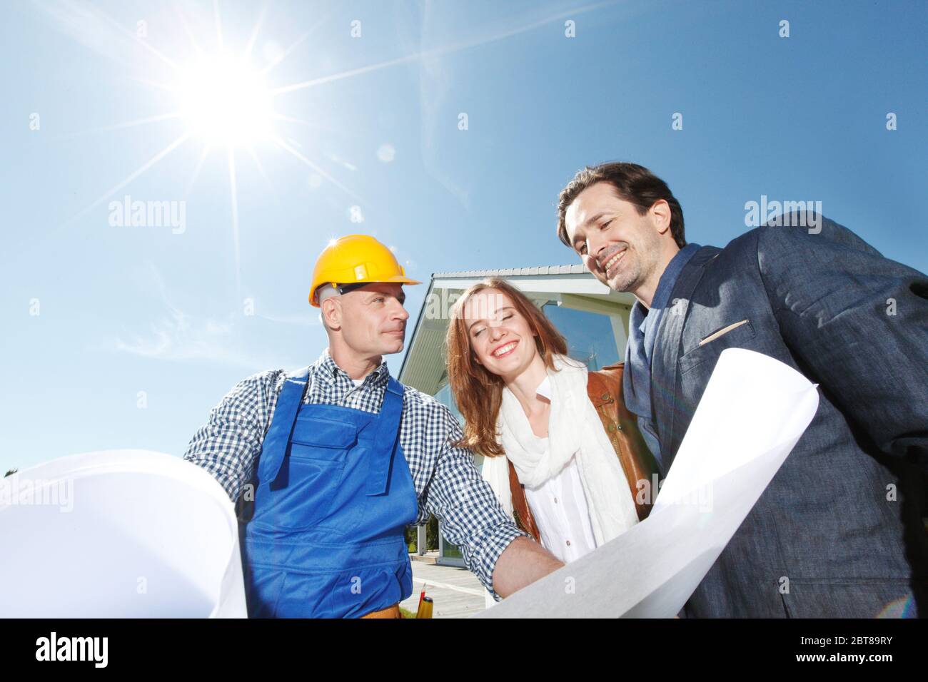 Foreman showing house design construction plan to a happy young couple ...