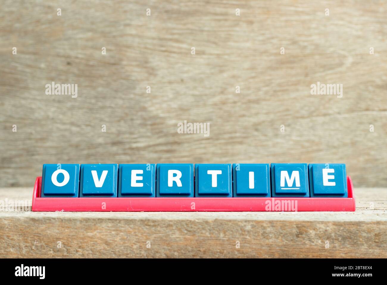 Tile letter on red rack in word overtime on wood background Stock Photo ...