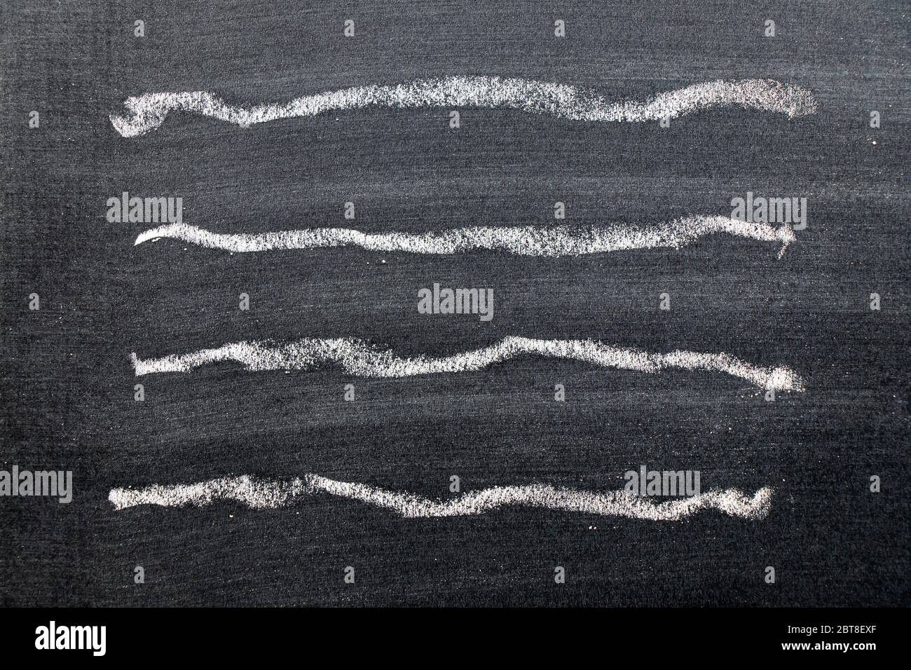 White color chalk hand drawing in set of wavy line shape on black board ...